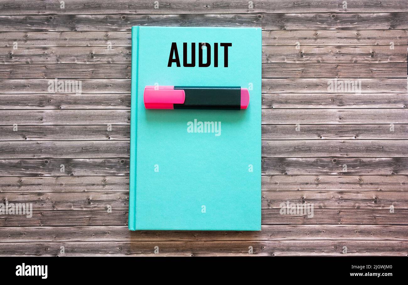 Audit word on a green diary with a felt-tip pen on a wooden background ...