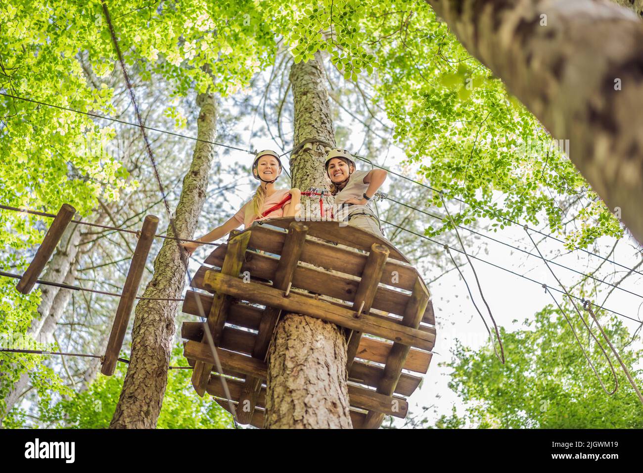 Two women girls female gliding climbing in extreme road trolley zipline ...