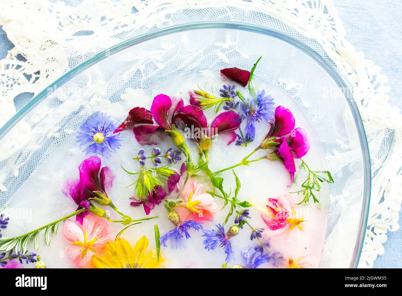 Summer background of frozen flowers in ice, cornflowers and geraniums ...