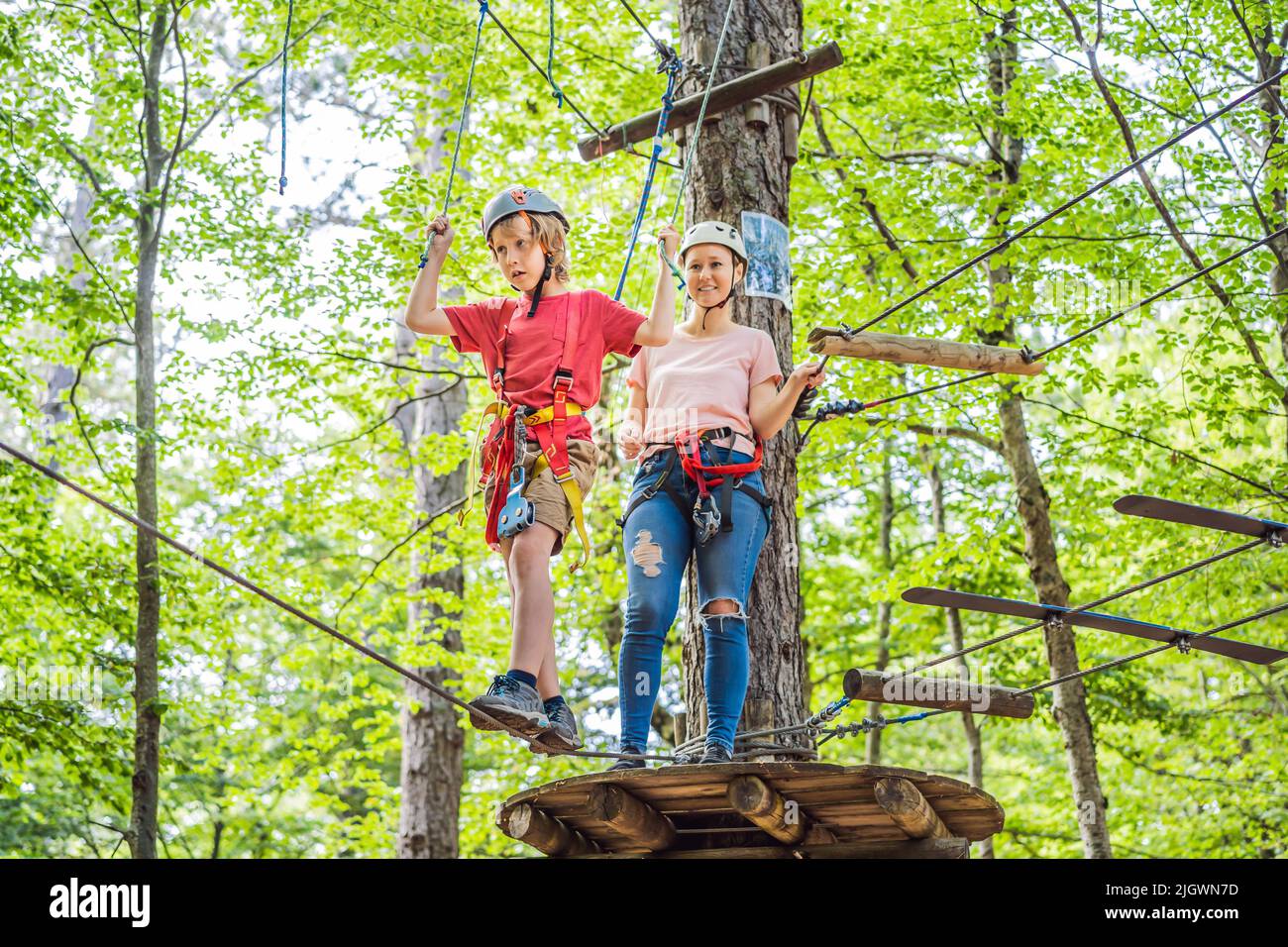Mother and son climbing in extreme road trolley zipline in forest on ...