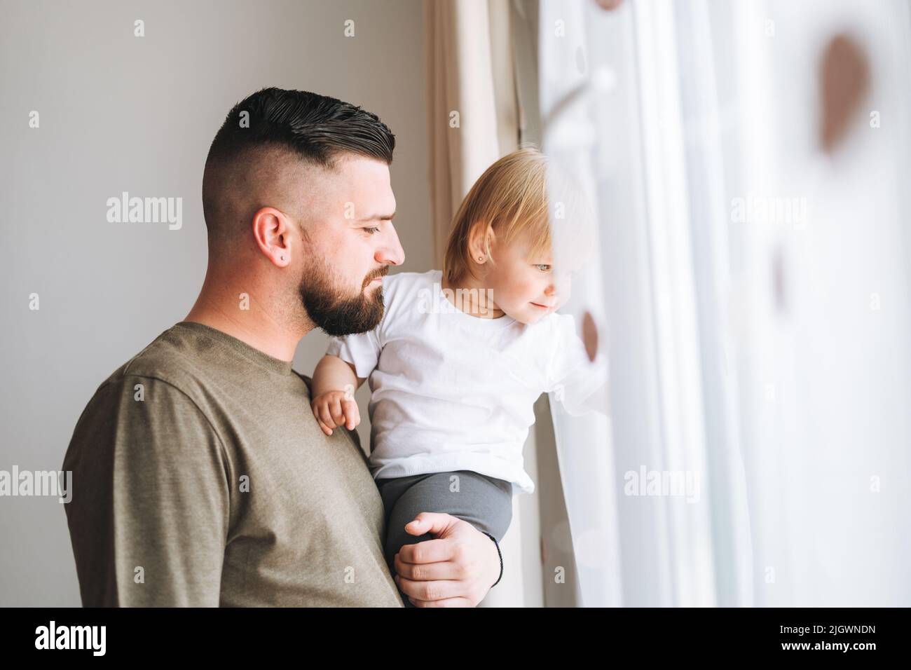 Multinational family, Young man father with baby girl on window sill ...