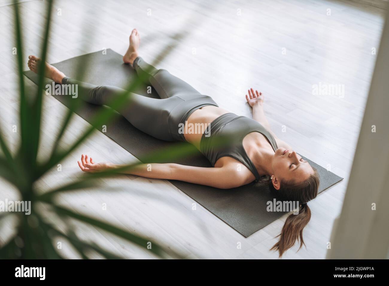 Young fit woman practice yoga doing savasana in light yoga studio with ...