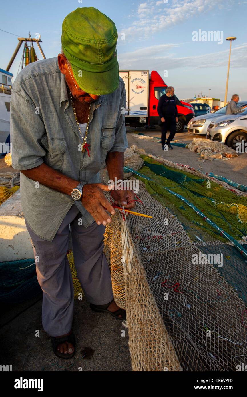 Europa, Italia, Sardegna, Porto Torres, Pescatore ripara le reti rotte ...