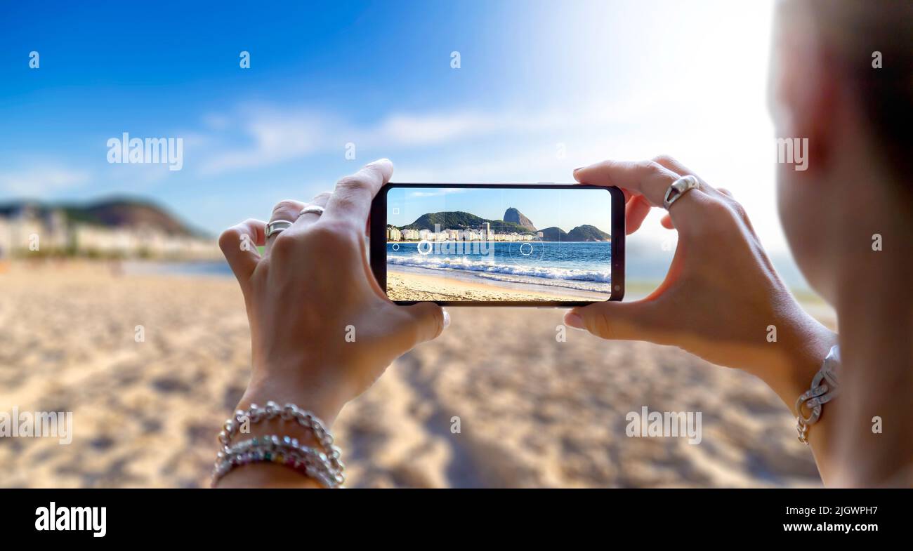 Woman in Copacabana Beach taking a photo with her mobile phone ...