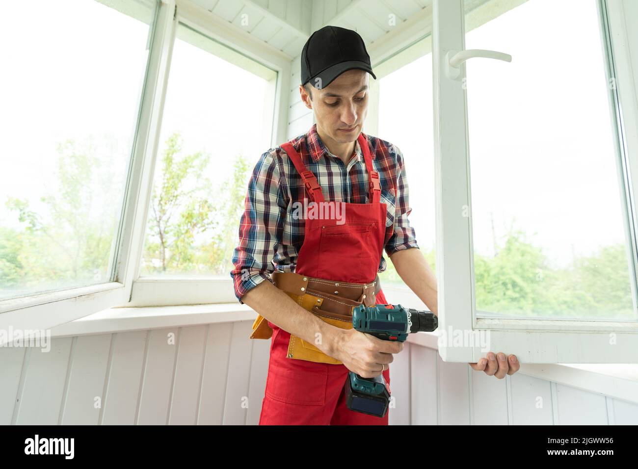Construction worker repairing plastic window with screwdriver indoors ...