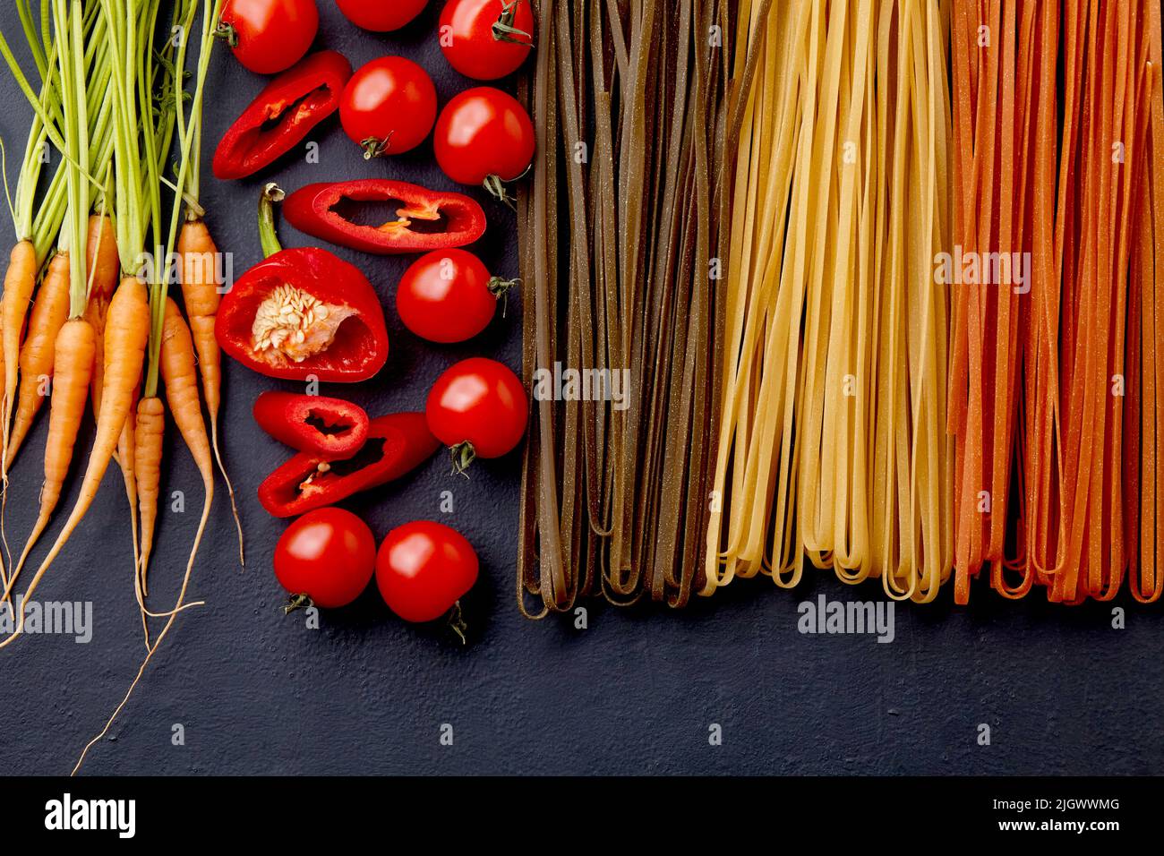 Homemade colorful pasta with natural ingredients on a black concrete ...