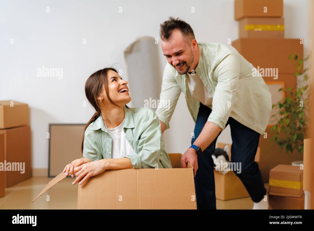 Young happy couple in room with moving boxes at new home Stock Photo ...