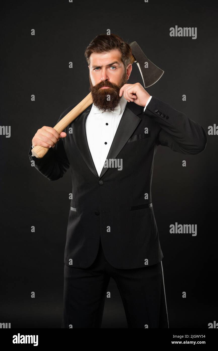 Serious bearded man twirling mustache while carrying axe at dark ...
