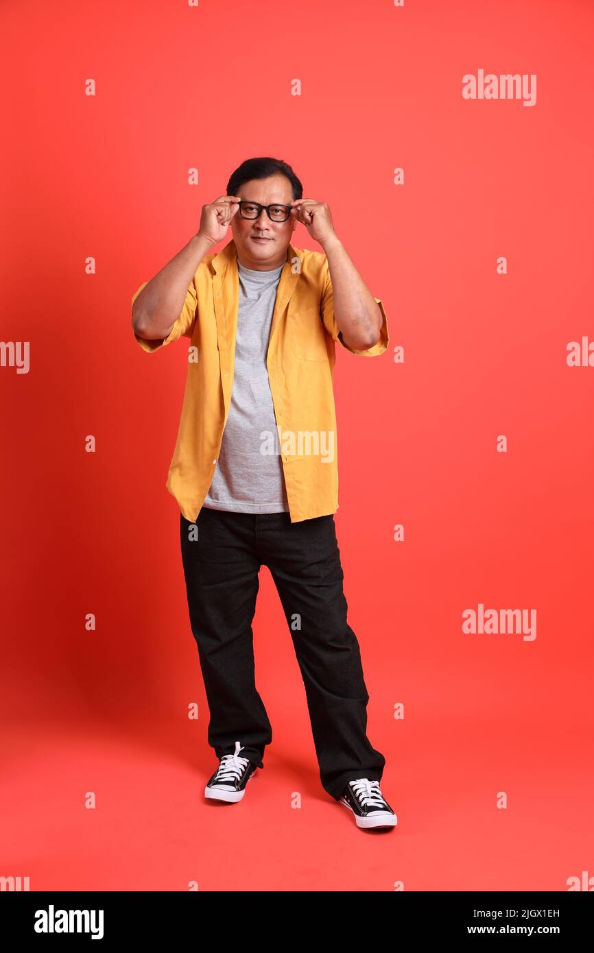 The adult Asian man with yellow shirt standing on the orange background ...