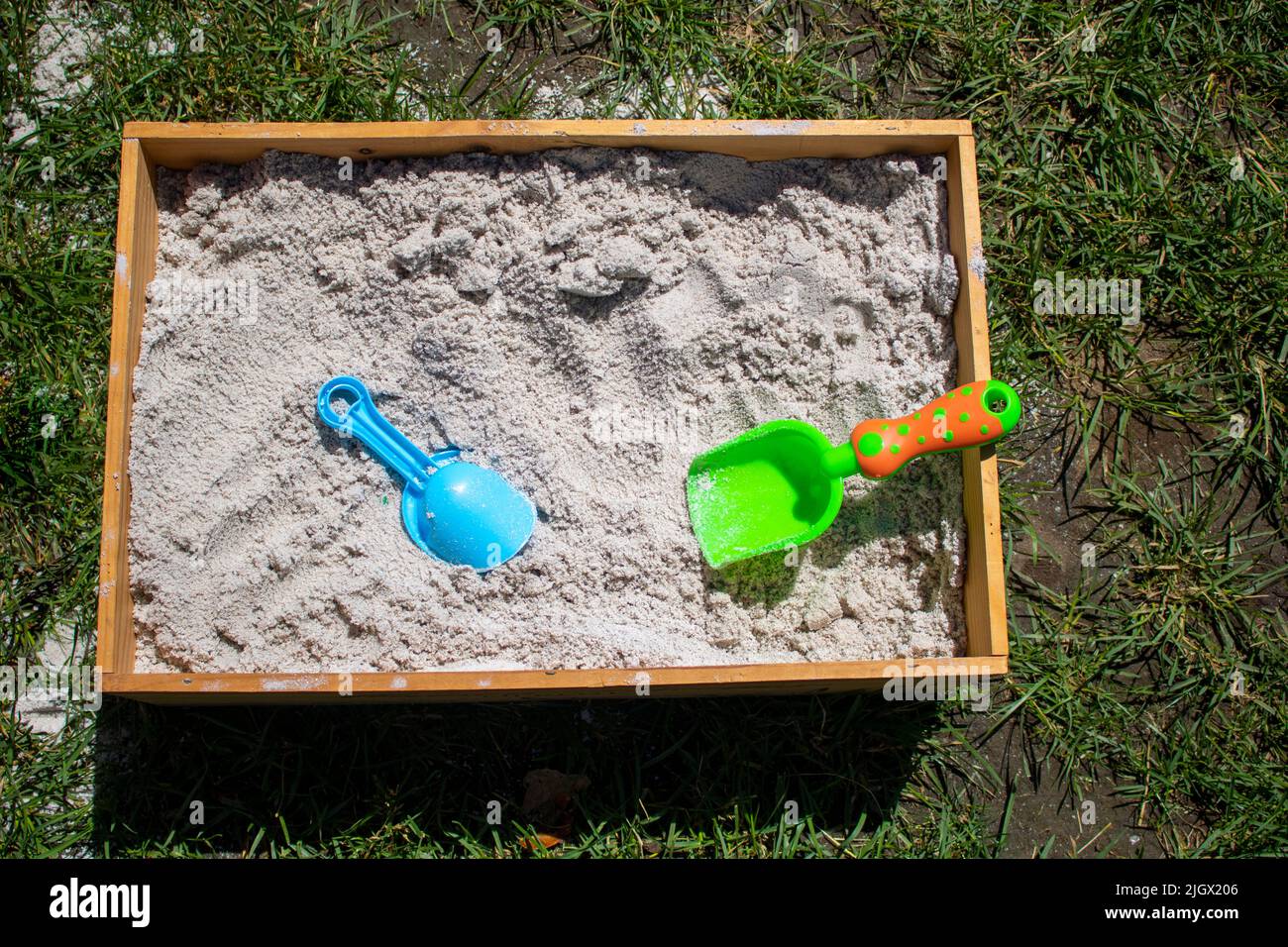 small home made wood frame infant sandbox with two plastic shovels ...
