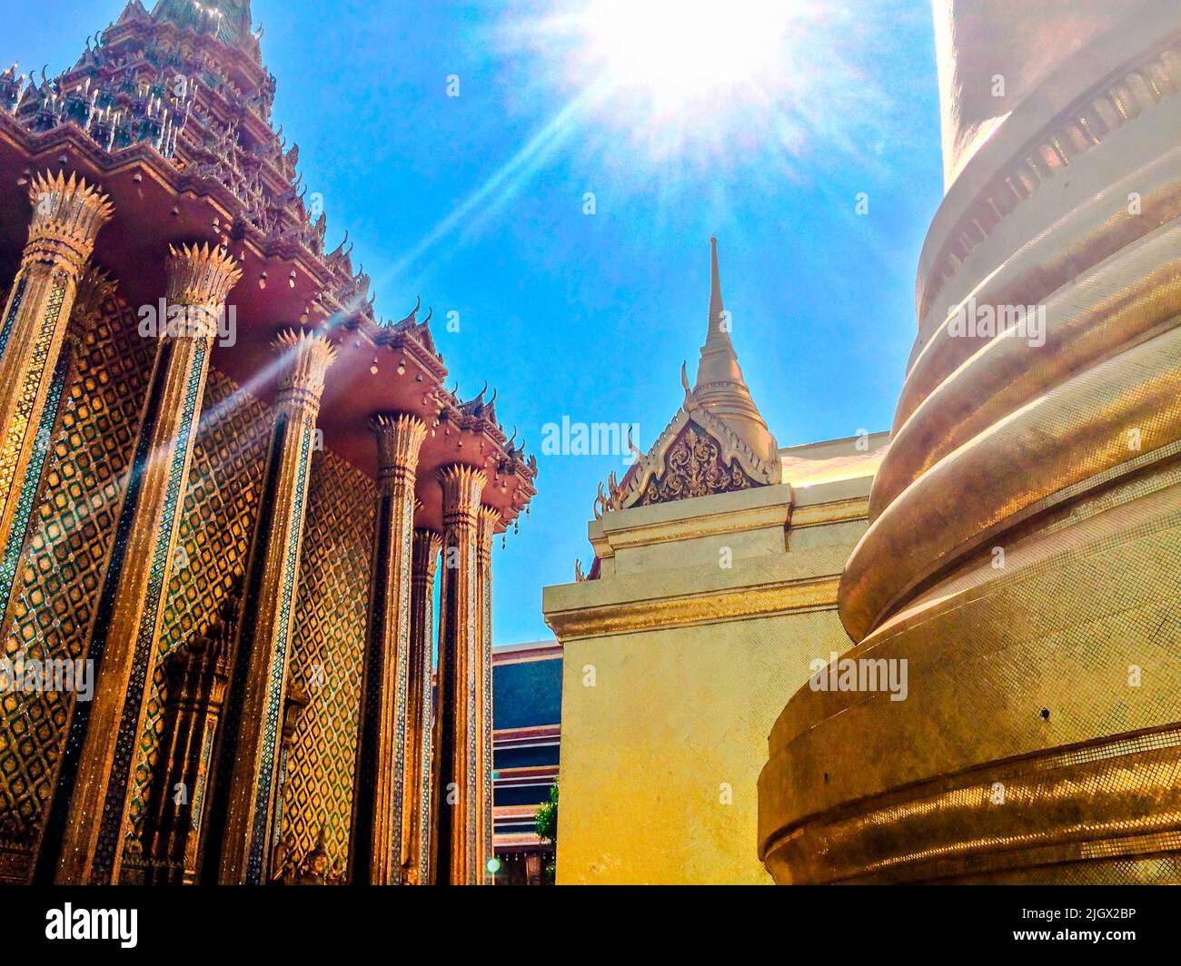 A view of three exterior golden buildings against a blue sky.at Wat Po ...