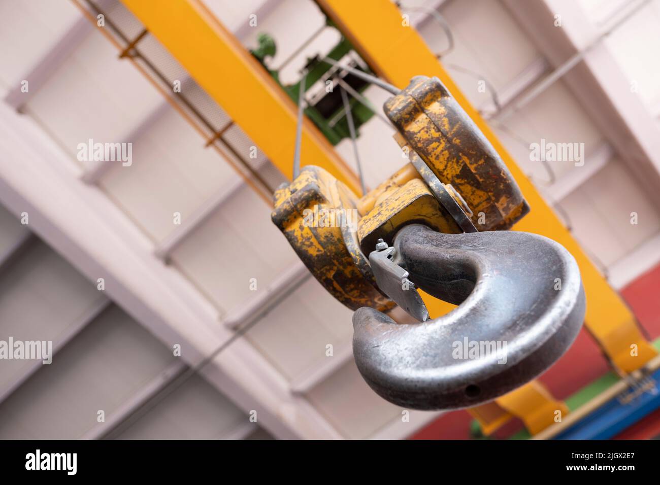 Old crane hook, bottom view in the factory. Industrial yellow old crane ...