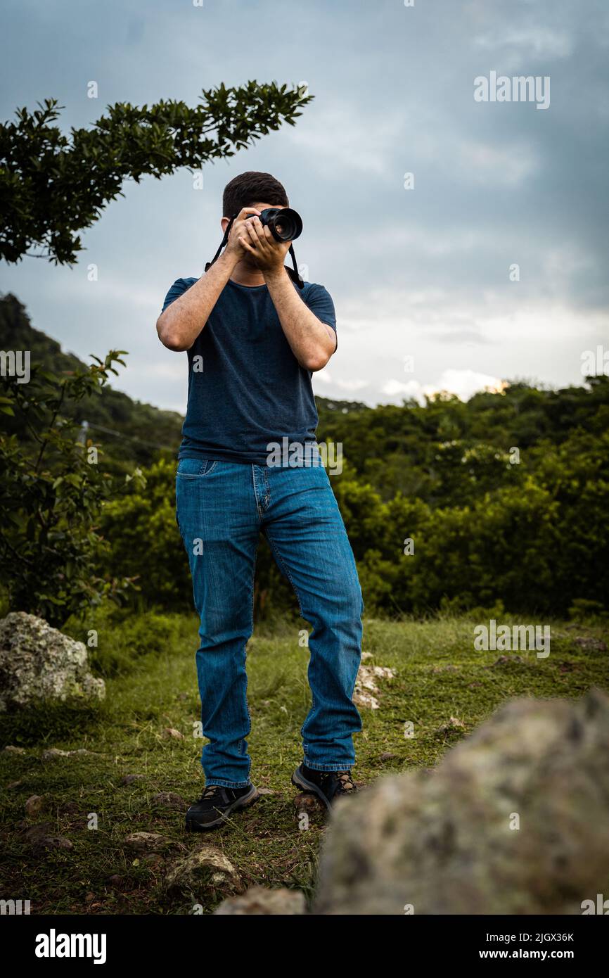 A vertical shot of a male photographer on meadow shooting landscape ...