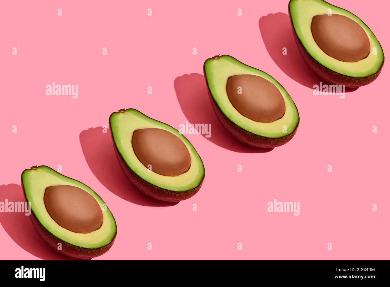 Colorful fruit pattern of fresh cutted avocado halves with pits on ...