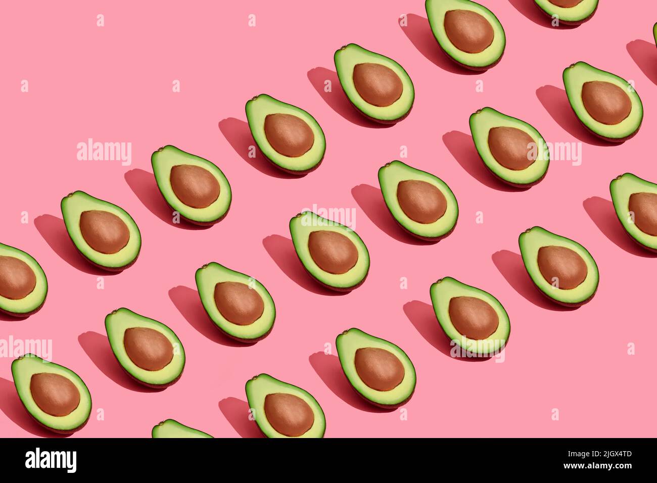 Colorful fruit pattern of fresh cutted avocado halves with pits on ...