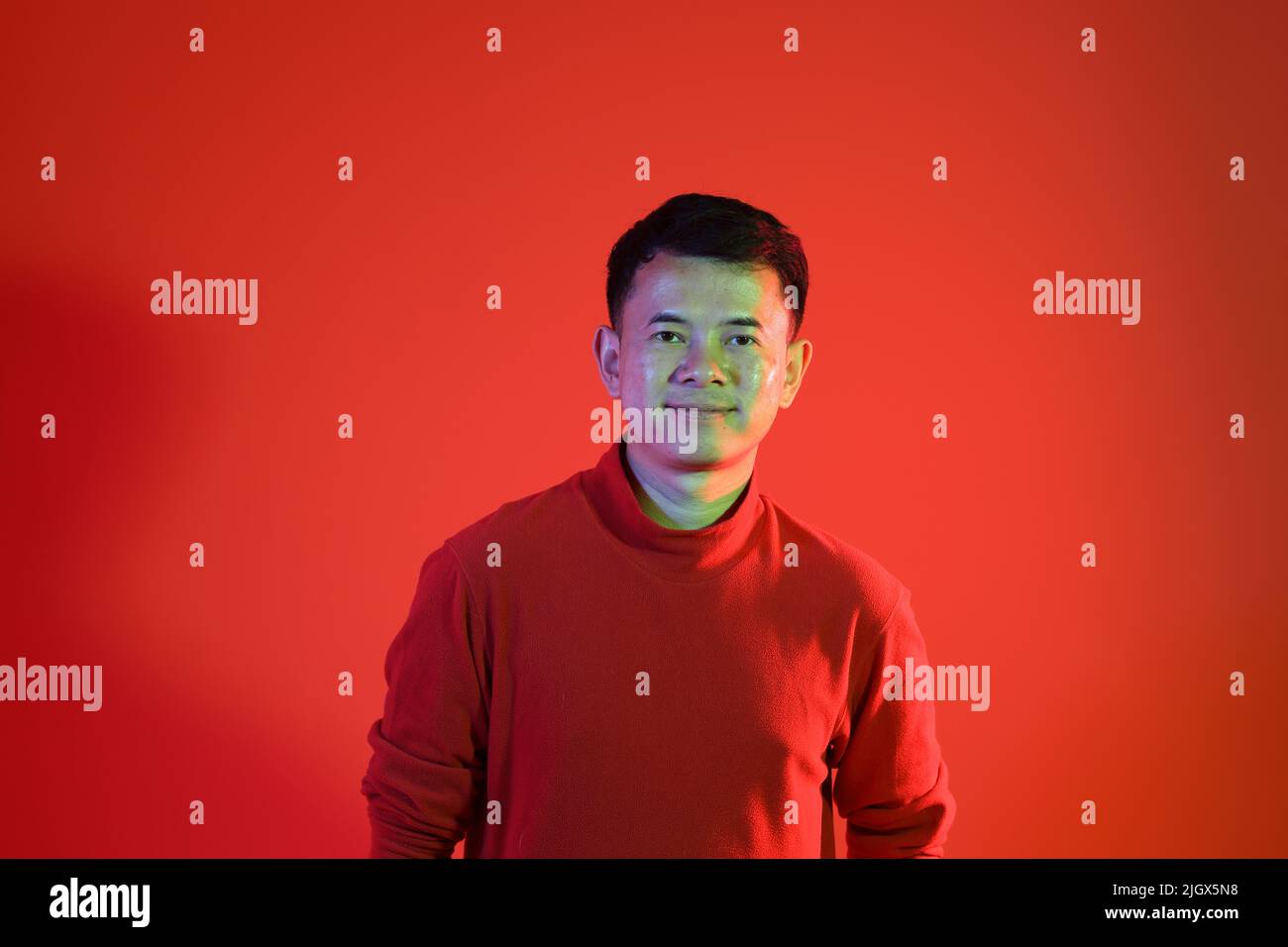 The cool adult Asian man on the blue background under the color gel ...