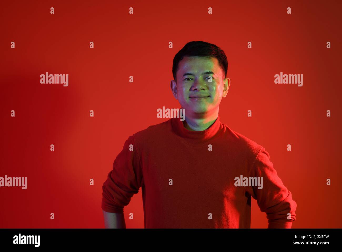 The cool adult Asian man on the blue background under the color gel ...