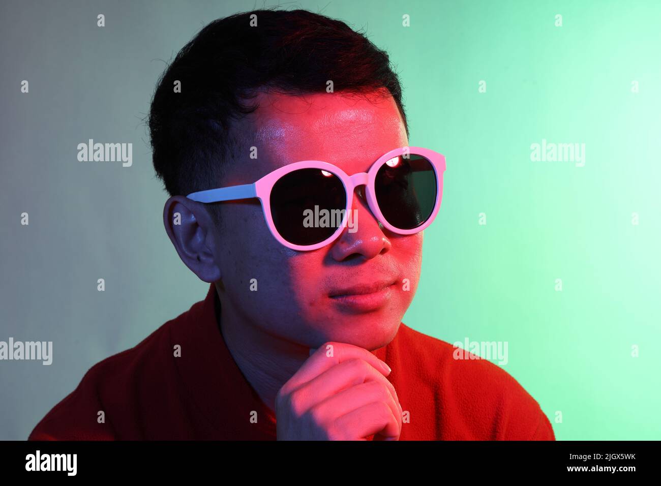 The cool adult Asian man on the blue background under the color gel ...