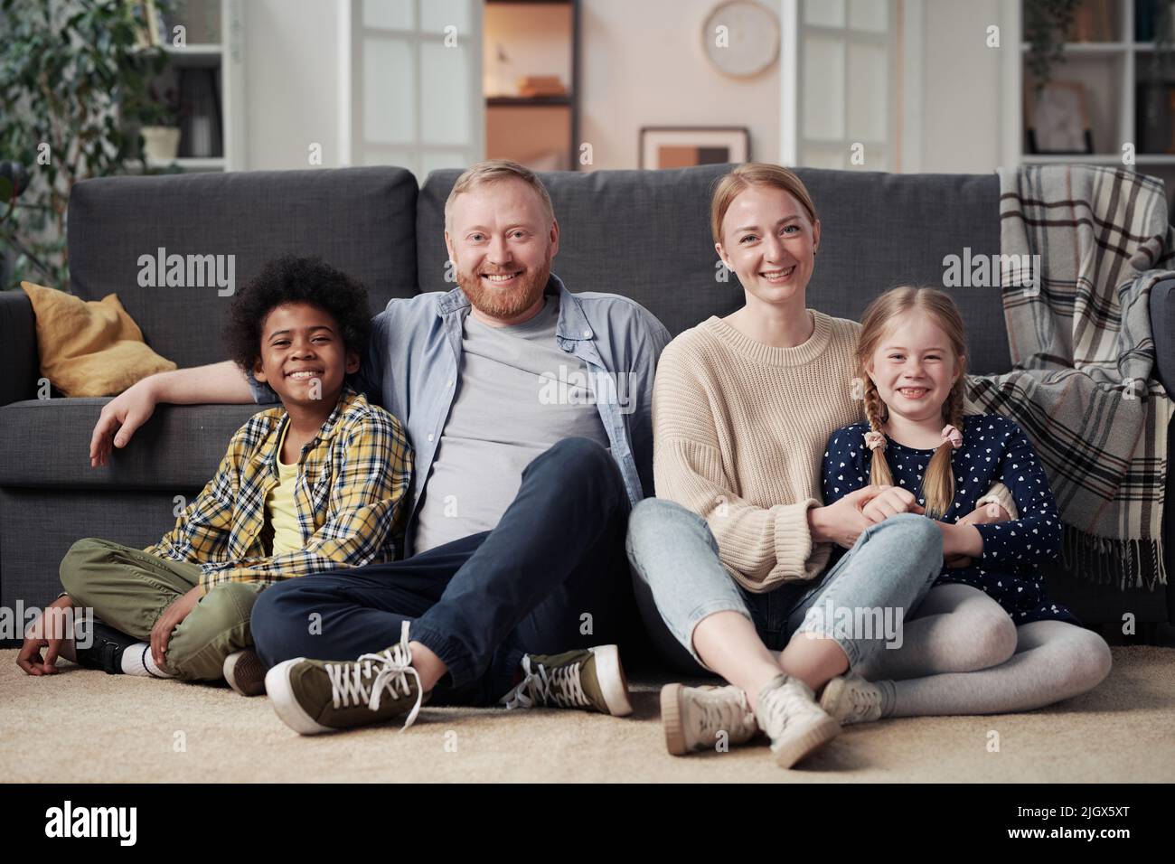 Portrait of happy family with adopted children sitting on floor in ...