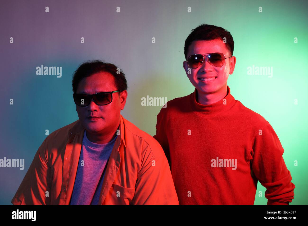 The cool adult Asian man on the blue background under the color gel ...