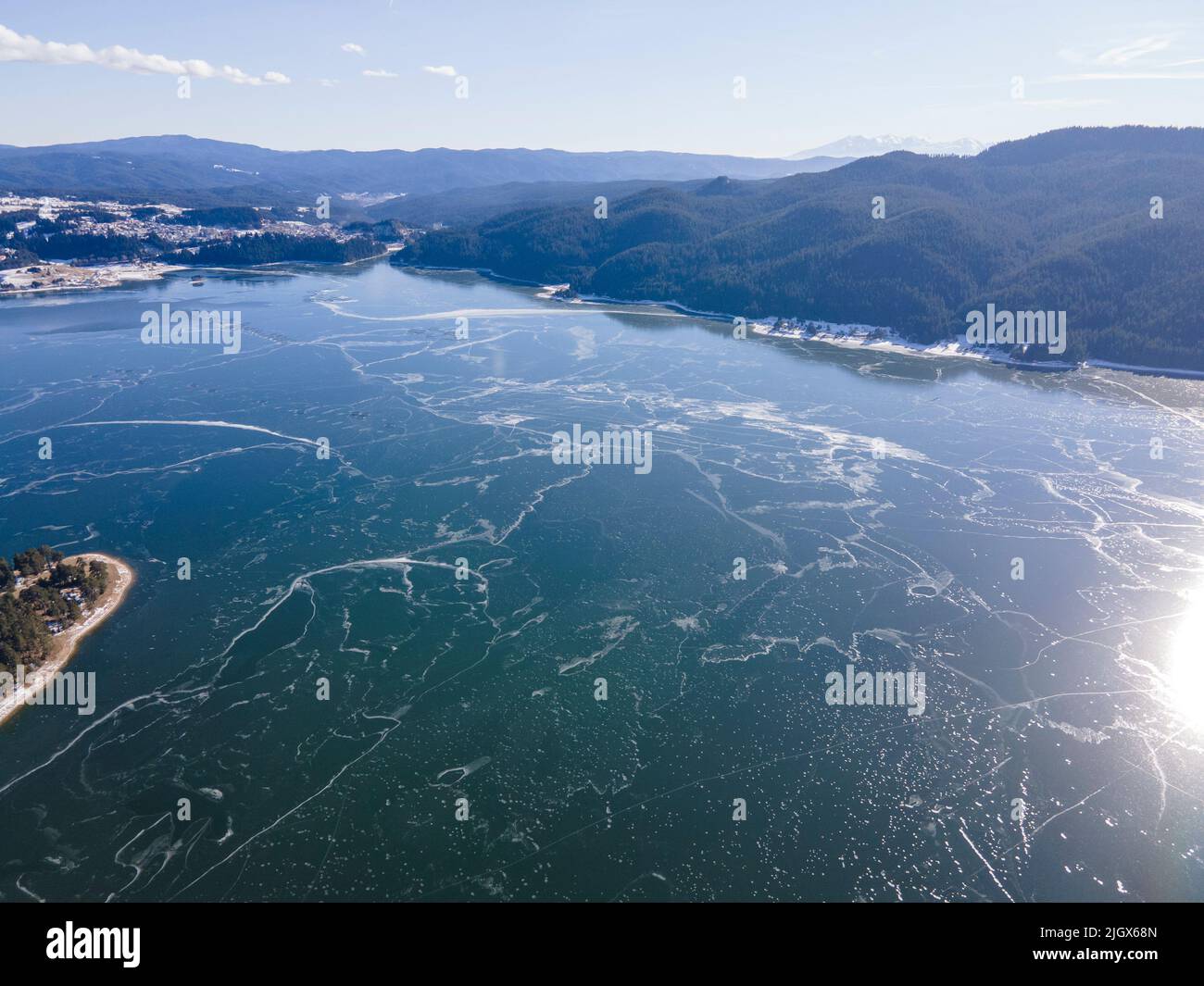 Aerial winter view of Dospat Reservoir covered with ice, Smolyan Region ...