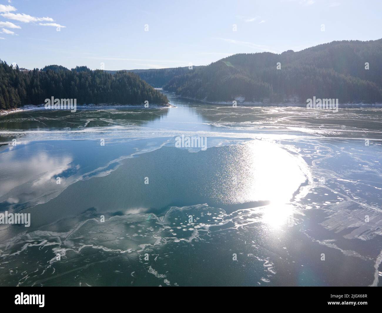 Aerial winter view of Dospat Reservoir covered with ice, Smolyan Region ...
