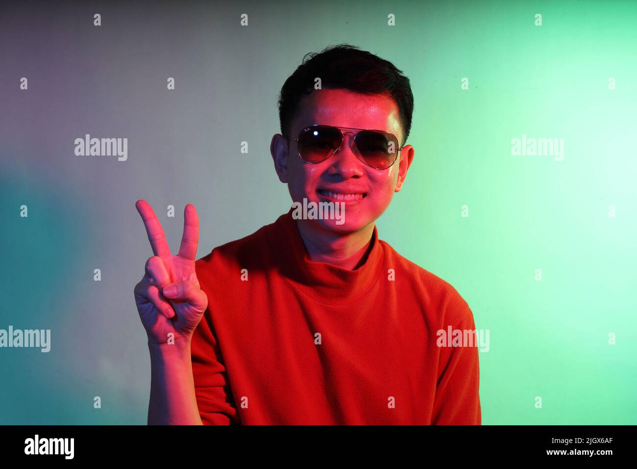 The cool adult Asian man on the blue background under the color gel ...