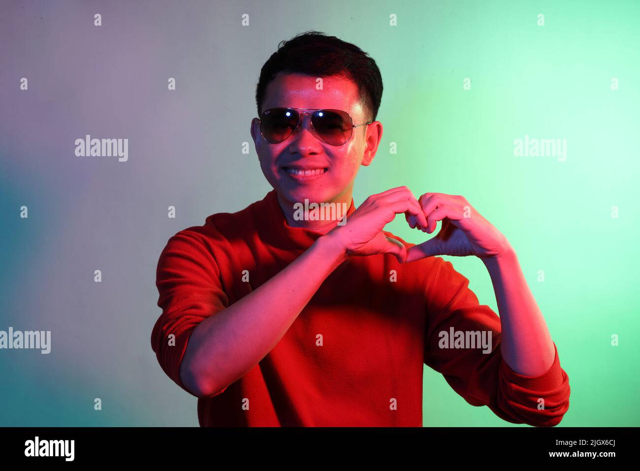 The cool adult Asian man on the blue background under the color gel ...