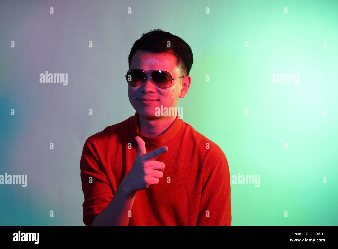 The cool adult Asian man on the blue background under the color gel ...