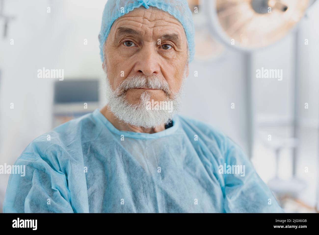 Professional senior surgeon in uniform standing in operating room ...