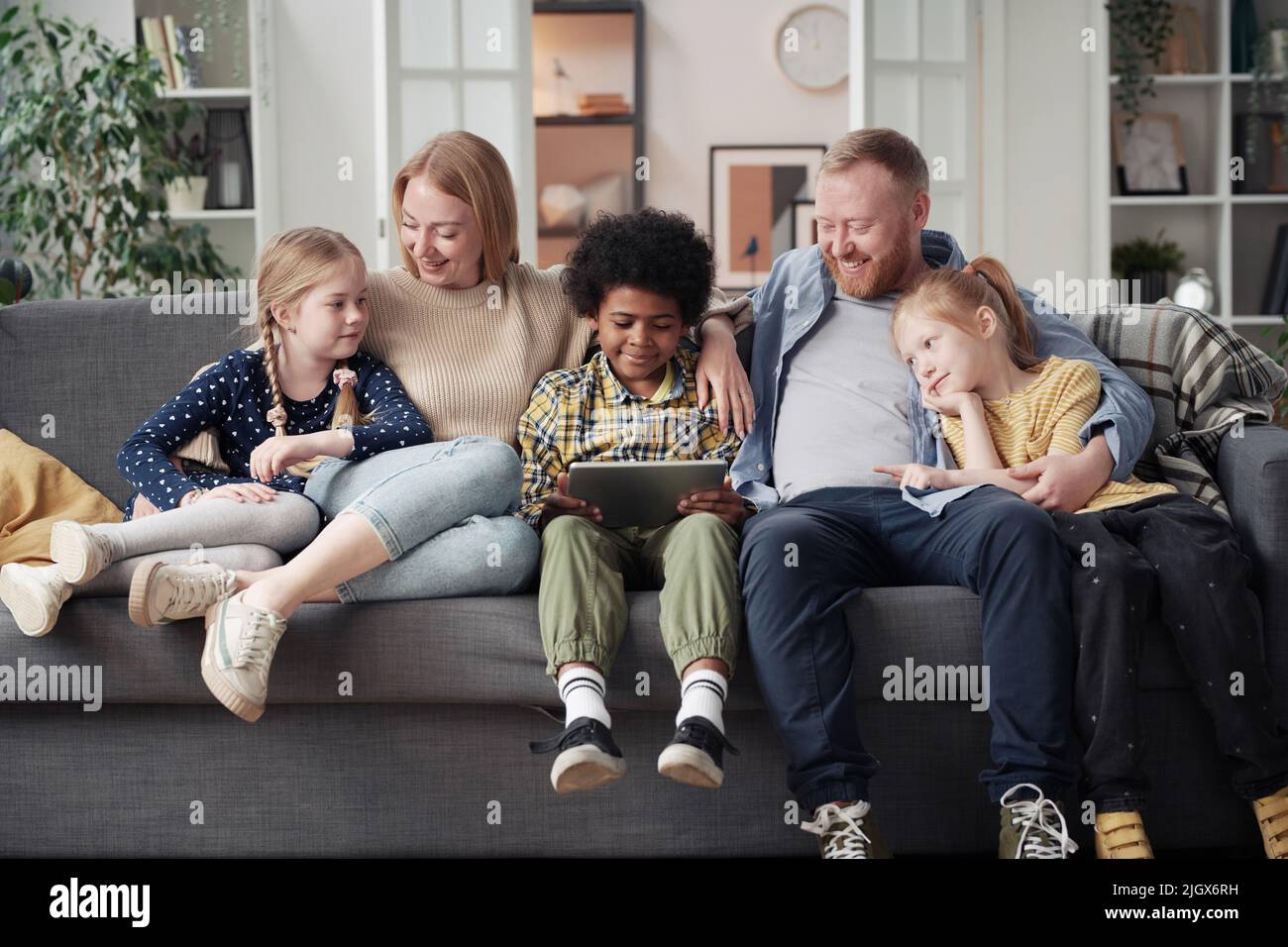 Adopted children watching cartoons on digital tablet and enjoying time ...