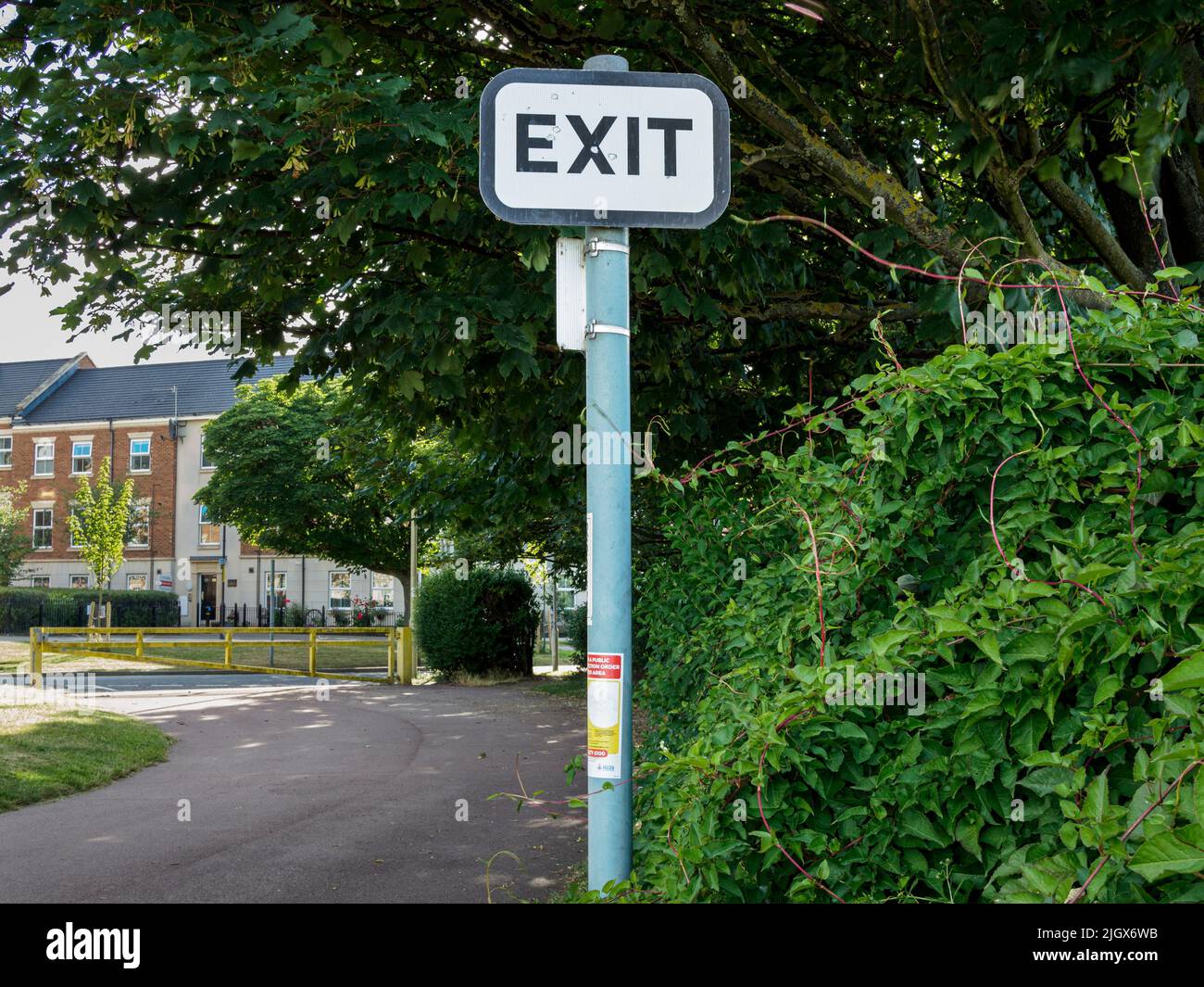 An old "Exit" sign on the road in a small town surrounded by green ...