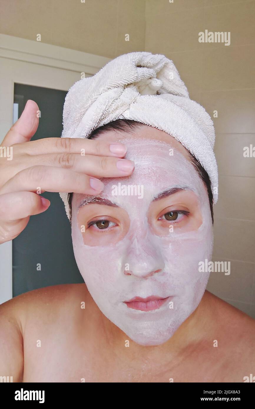 Candid woman applies mask of clay, minerals and salts to her face in ...