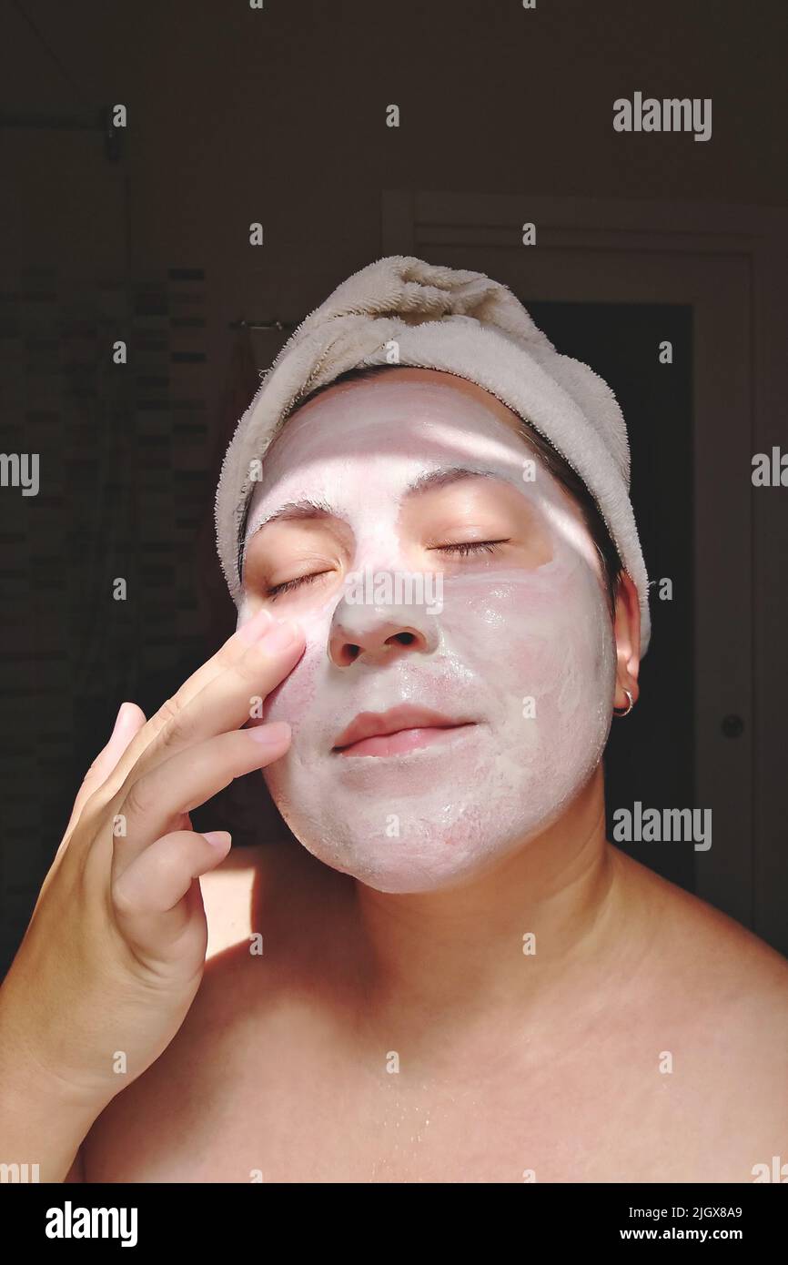 Candid woman applies mask of clay, minerals and salts to her face in ...