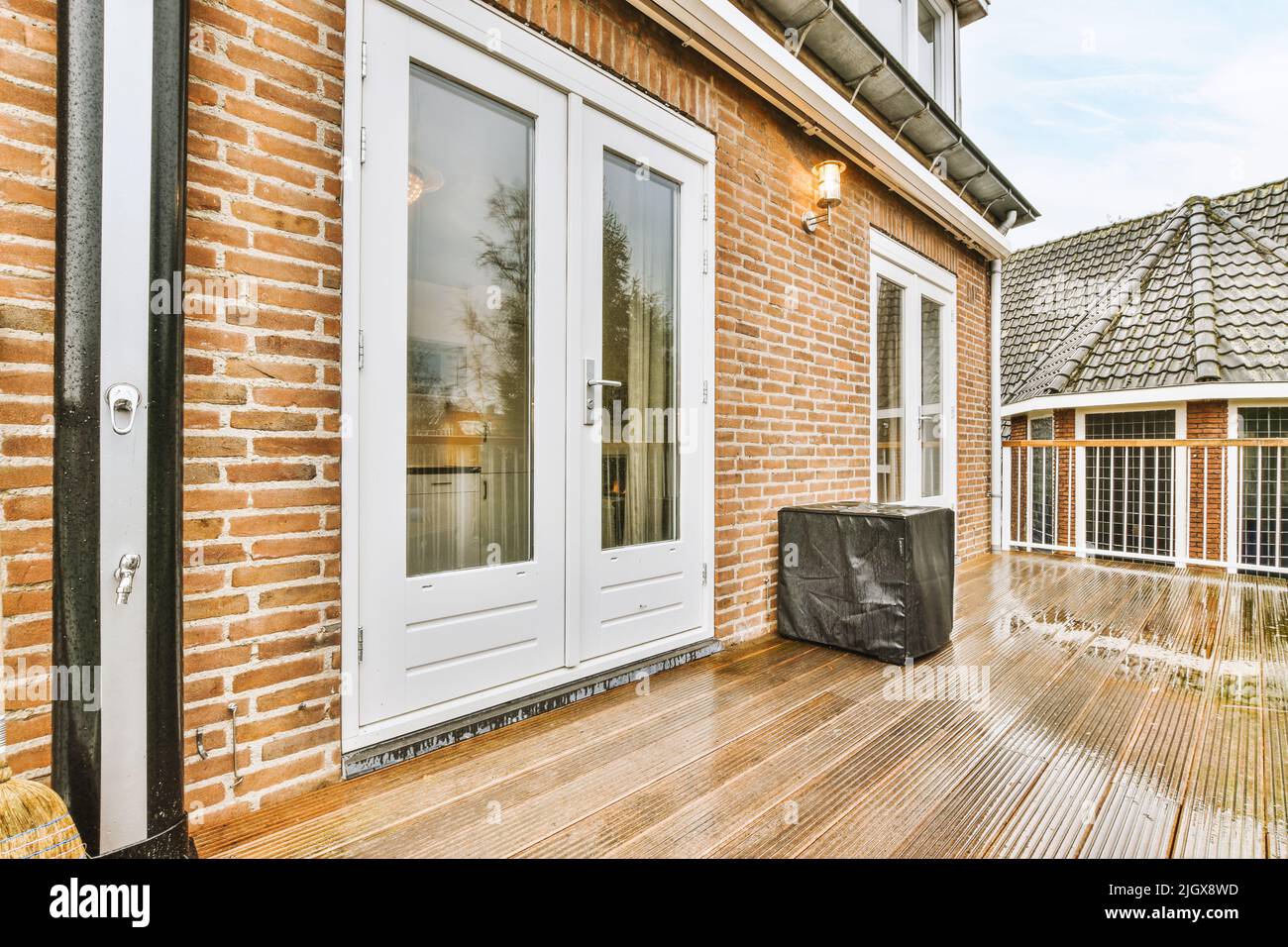 Brick balcony with metal railings, wooden chair and door with glass ...