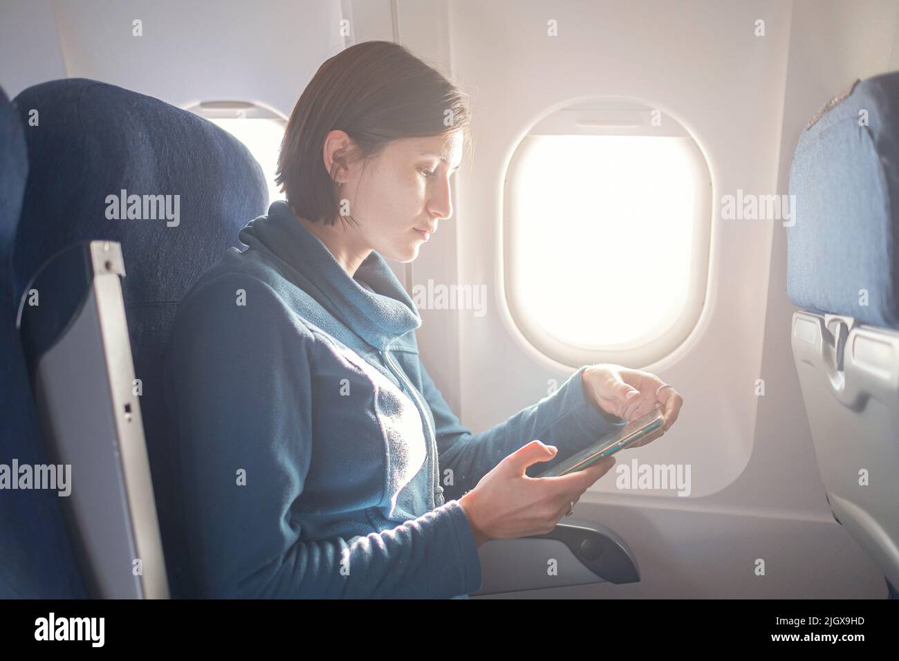 Young beautiful woman sitting at window of plane during the flight ...