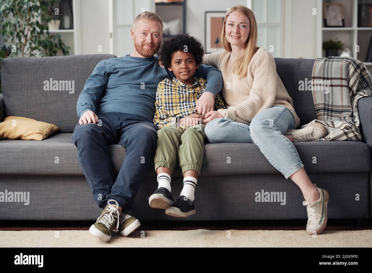 Portrait of young couple sitting on sofa in living room with their ...