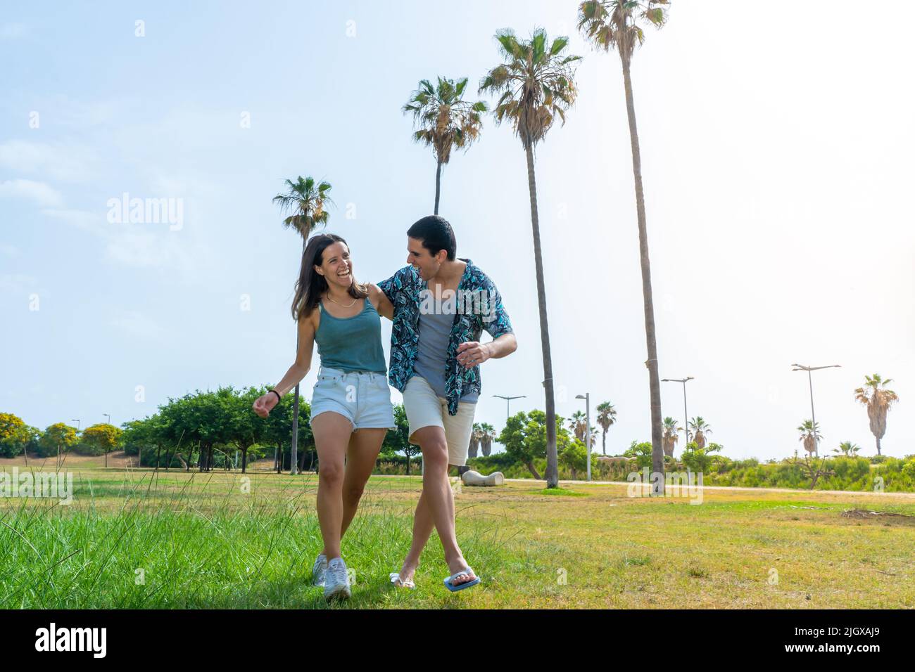 Happy friends walking laughing and holding each other in beautiful park ...