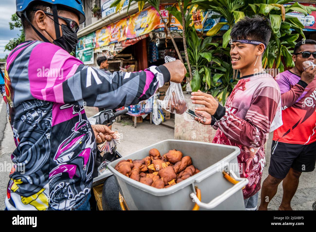 A happy customer takes away some fried banana snacks after purchasing ...