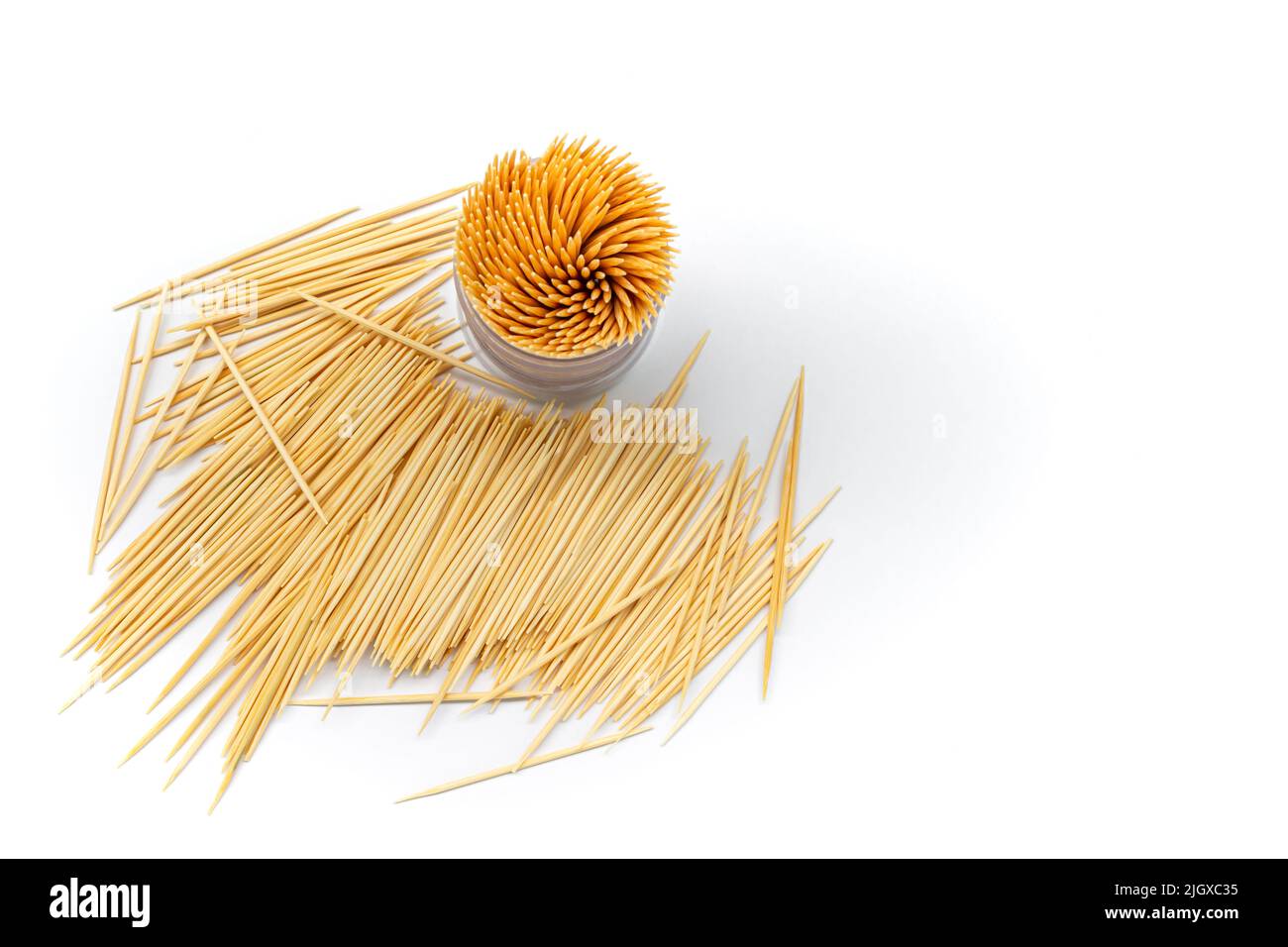 Pile of round wooden toothpicks and toothpick box with a plastic cover ...