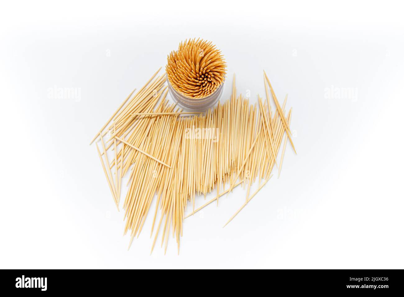 Pile of round wooden toothpicks and toothpick box with a plastic cover ...