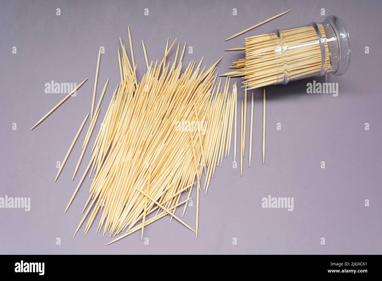 Pile of round wooden toothpicks and toothpick box with a plastic cover ...