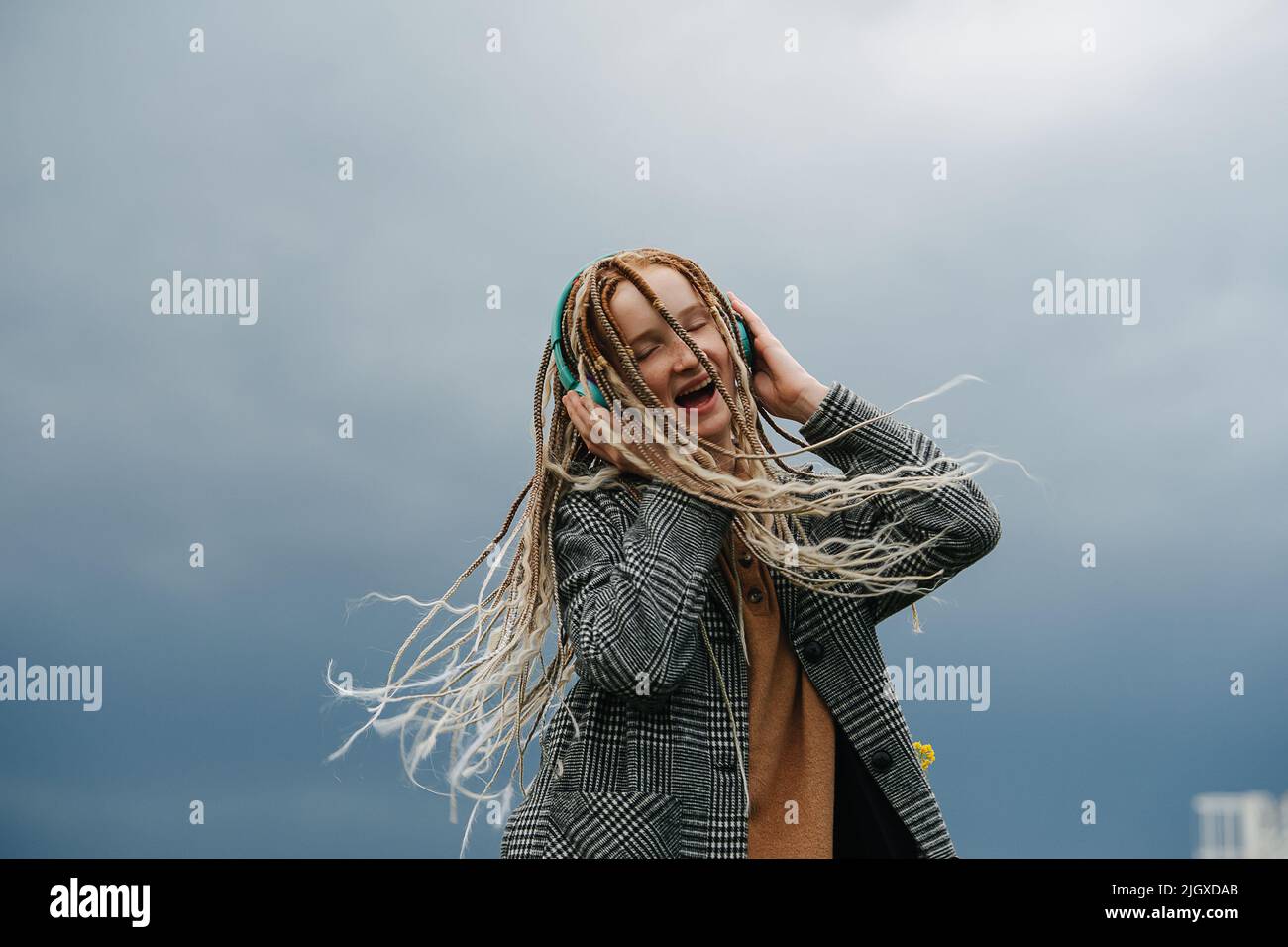 Hyped teenage girl with dreads listening music, shaking her head ...