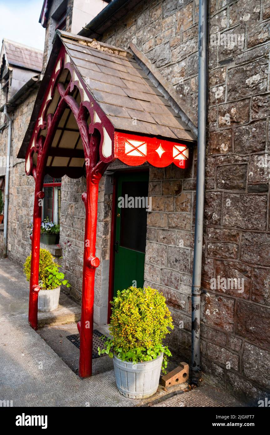Painted tree branch columns and carved bargeboard on stone cottages in ...