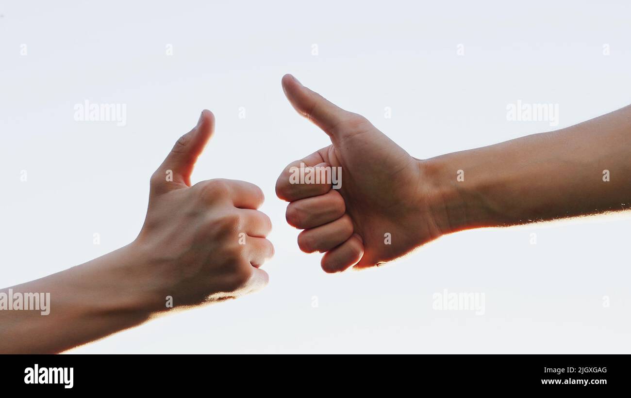 two hands shows thumbs up on blue sky background. Big finger up ...