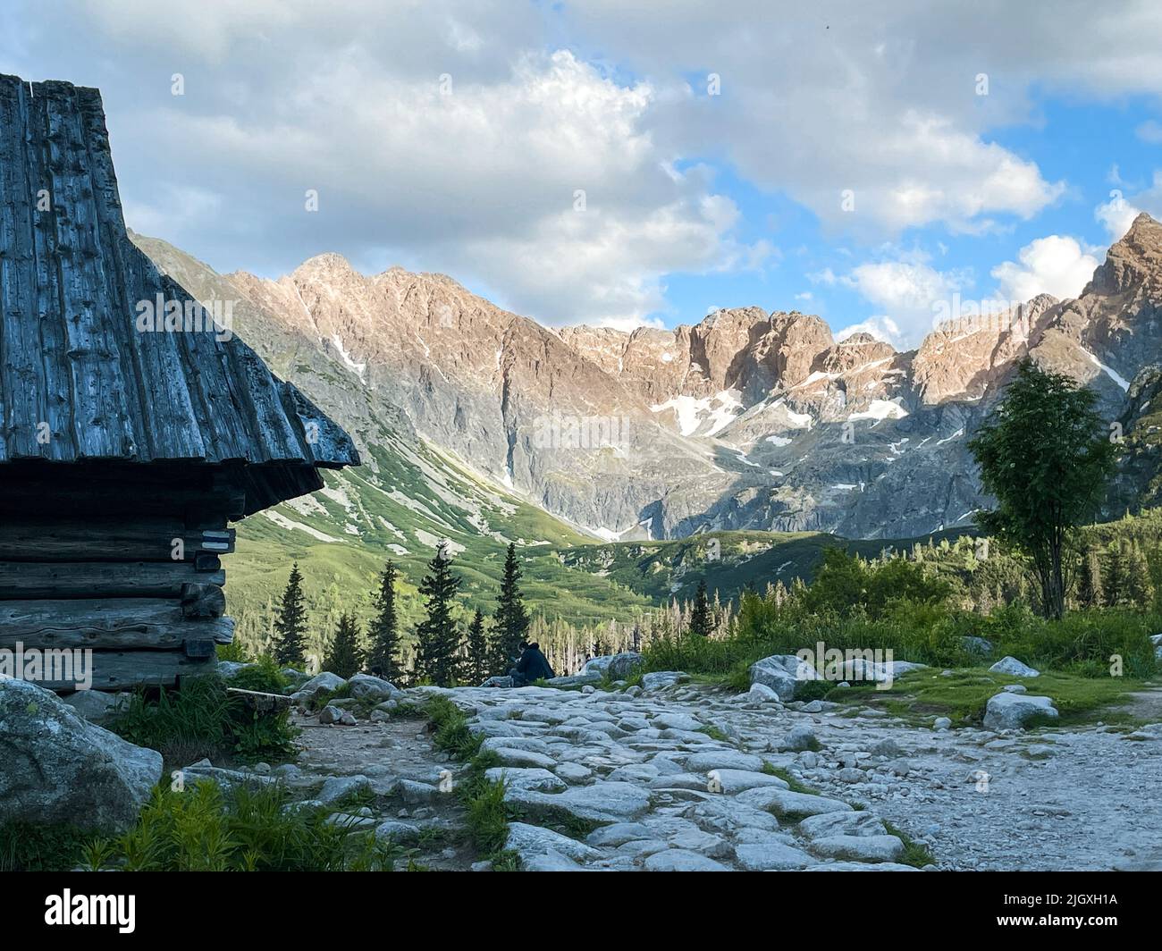 Mountain valley view with rocky path and mountain hut Stock Photo - Alamy
