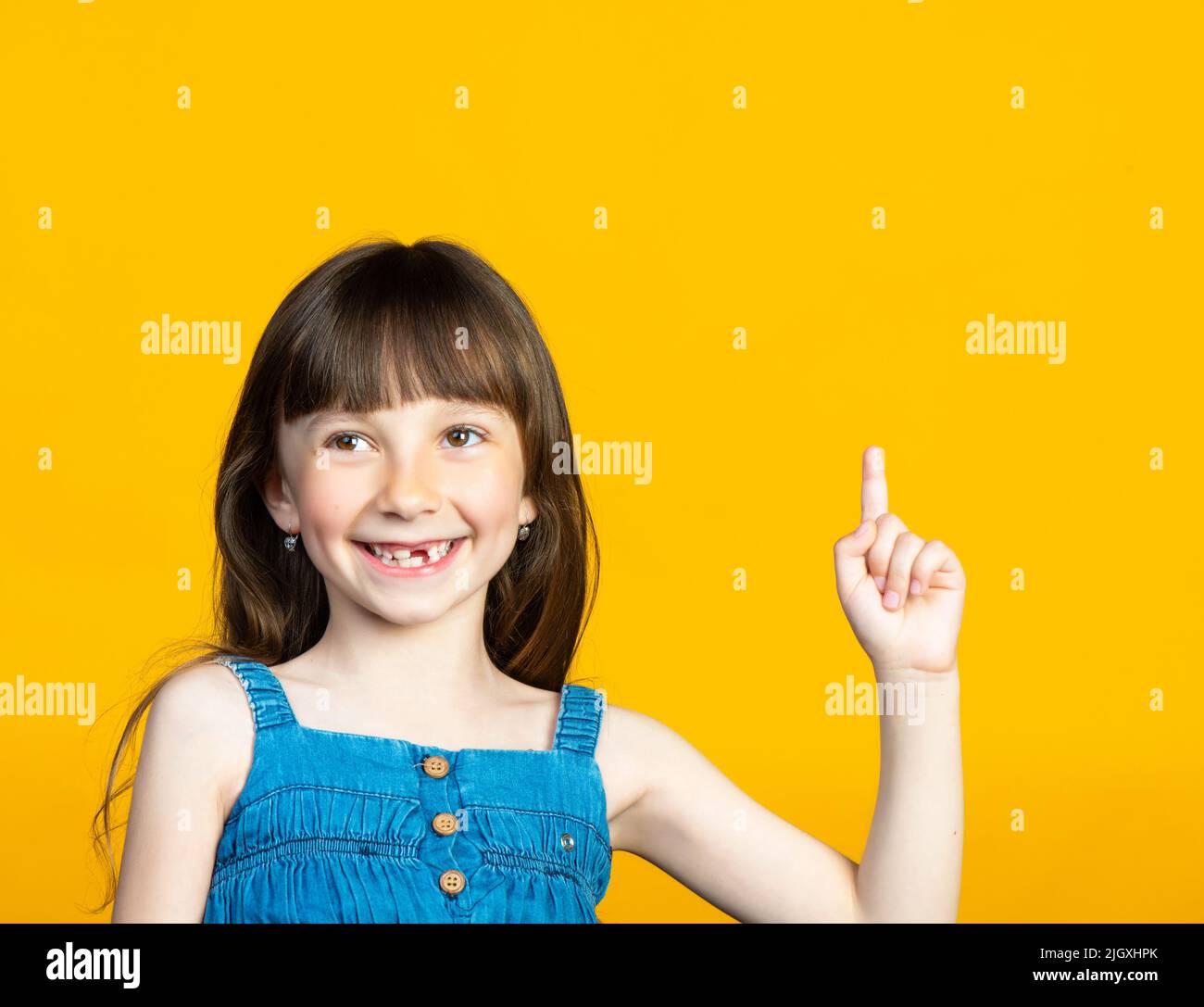 A cute little girl smiles a toothless smile with her front tooth ...