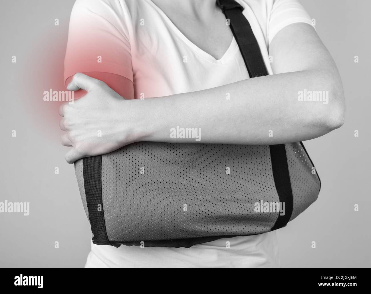 Woman wearing sling to support injured shoulder with red spot. Arm ...