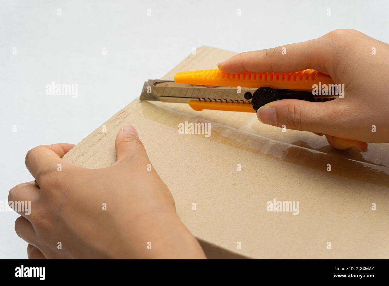 Unboxing the courier box with a cutter knife Stock Photo - Alamy
