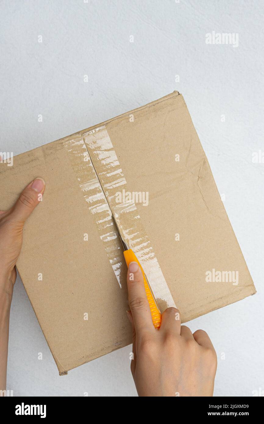 Unboxing the courier box with a cutter knife Stock Photo - Alamy